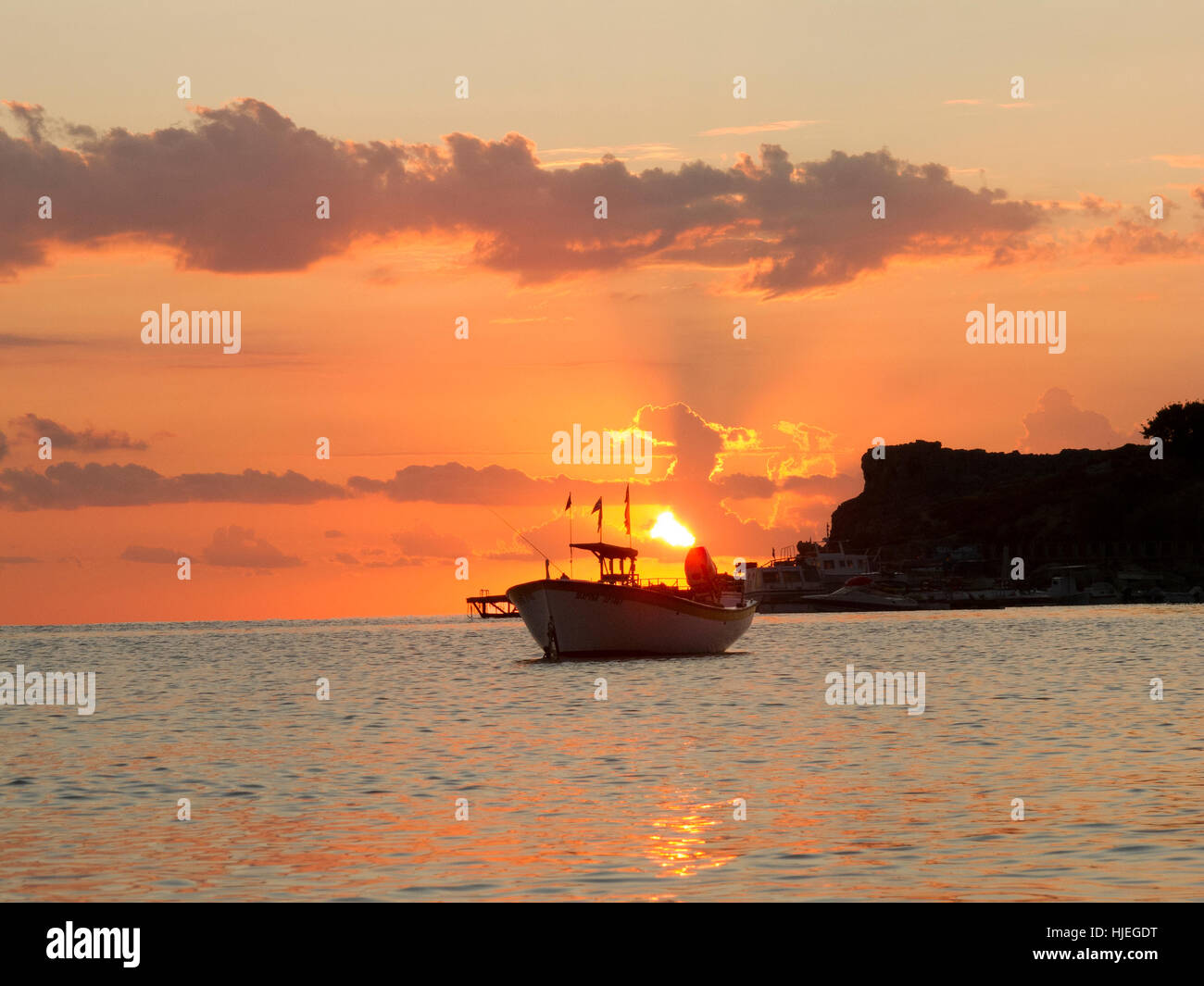 Boat at sunrise in bay at Lindos Rhodes Stock Photo - Alamy