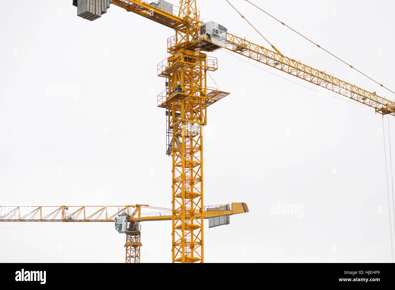 Two modern yellow construction cranes above sky Stock Photo - Alamy