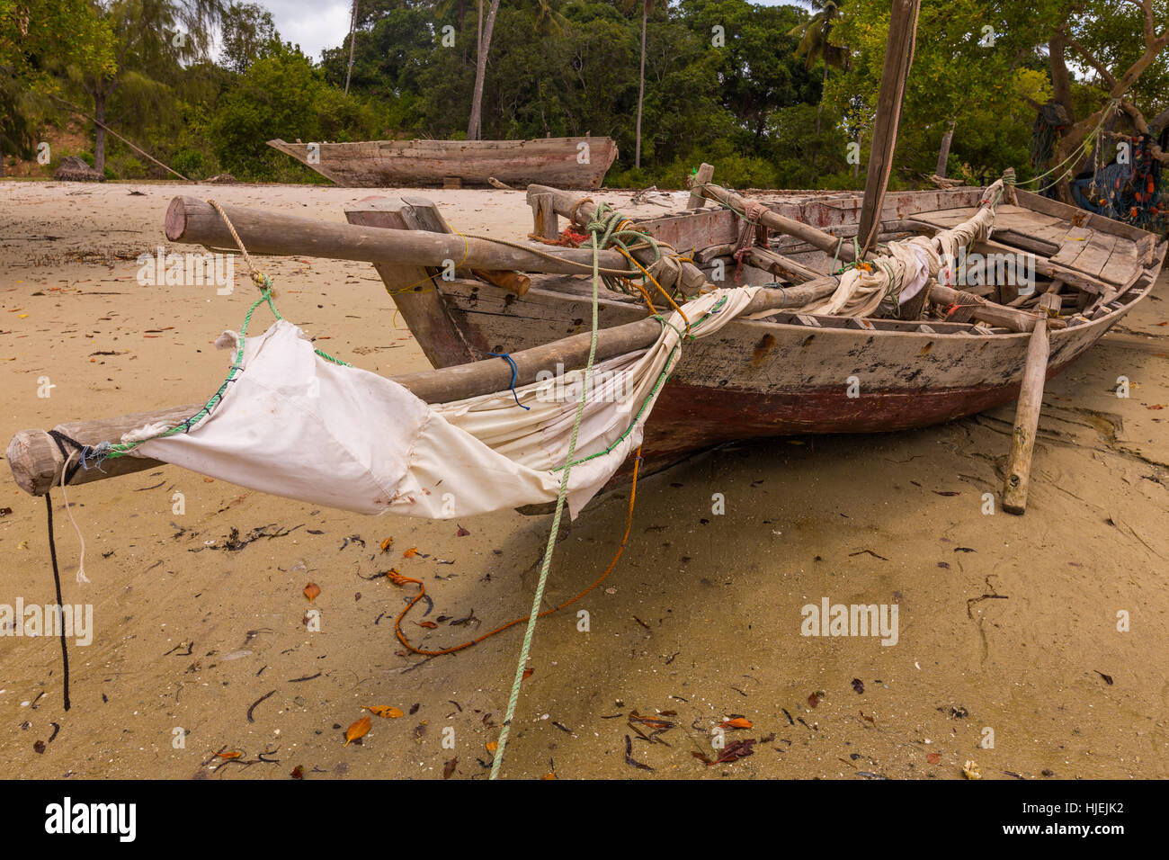 Big primitive fisherman wooden boat on beach with white sails and thin ...