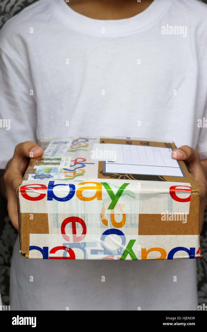 Hand holding a package bought on online auction - eBay Stock Photo - Alamy