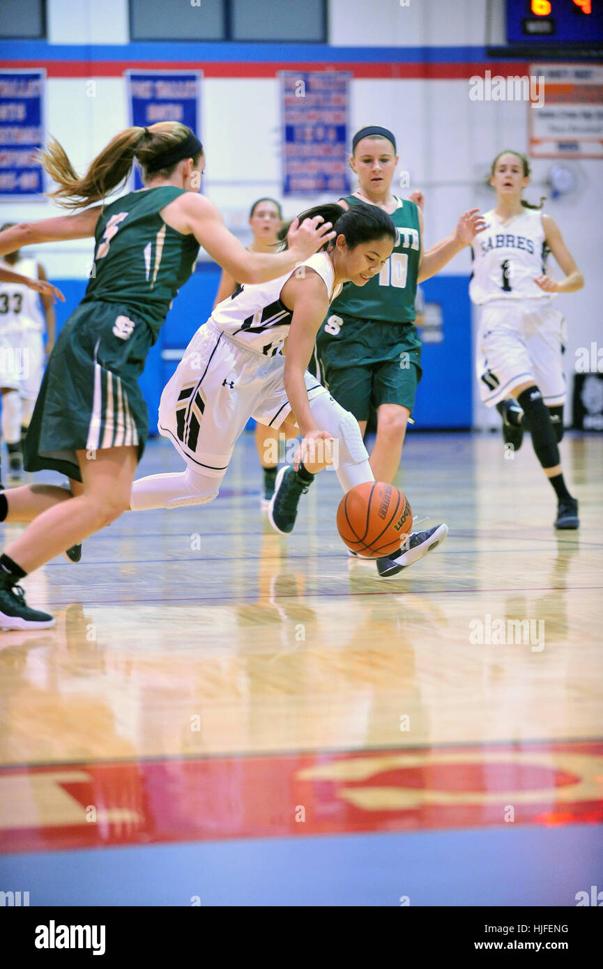High school player trying to control a loose ball off a dribble as she ...