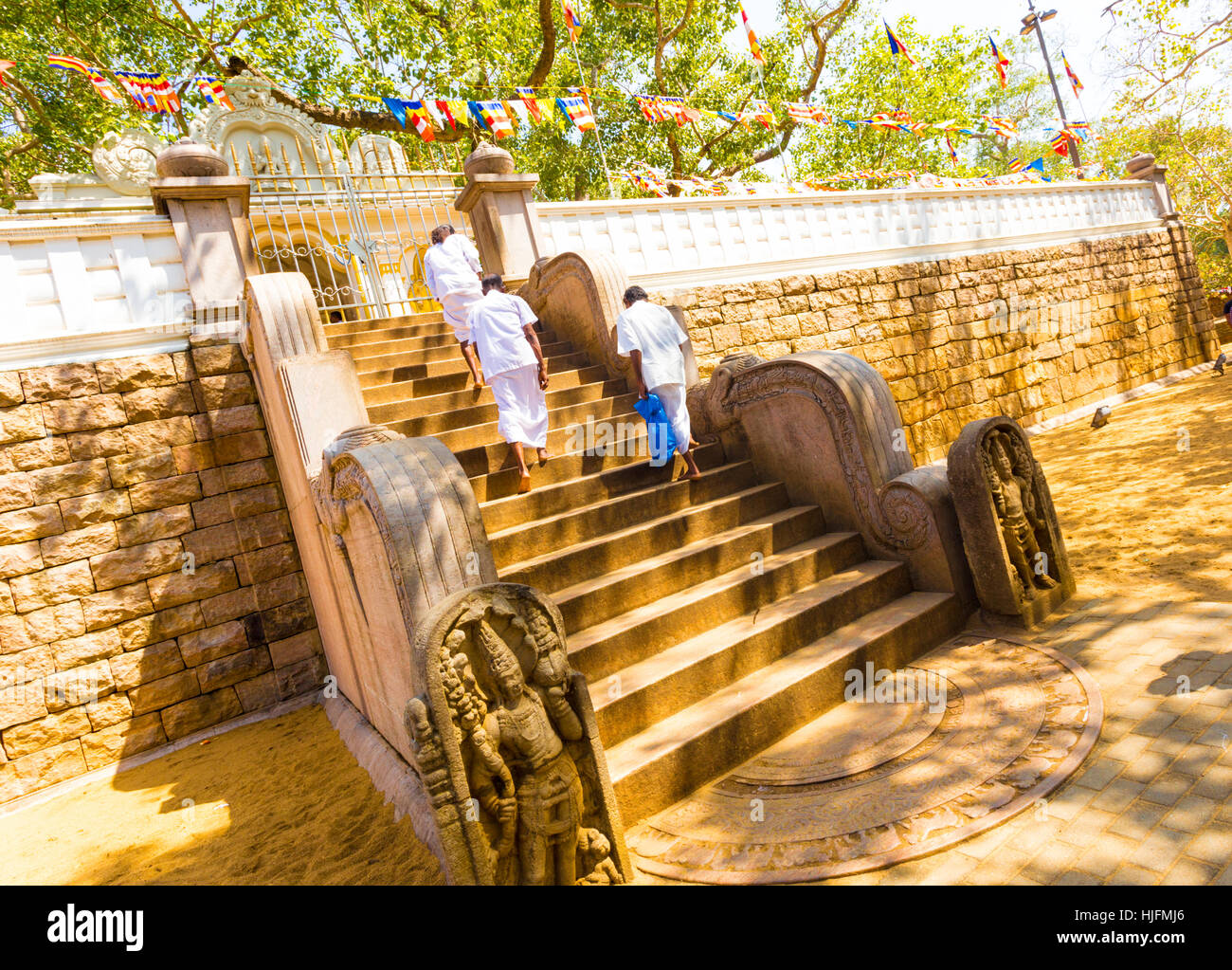 People walking past carved moonstone at base of steps to Jaya Sri Maha ...
