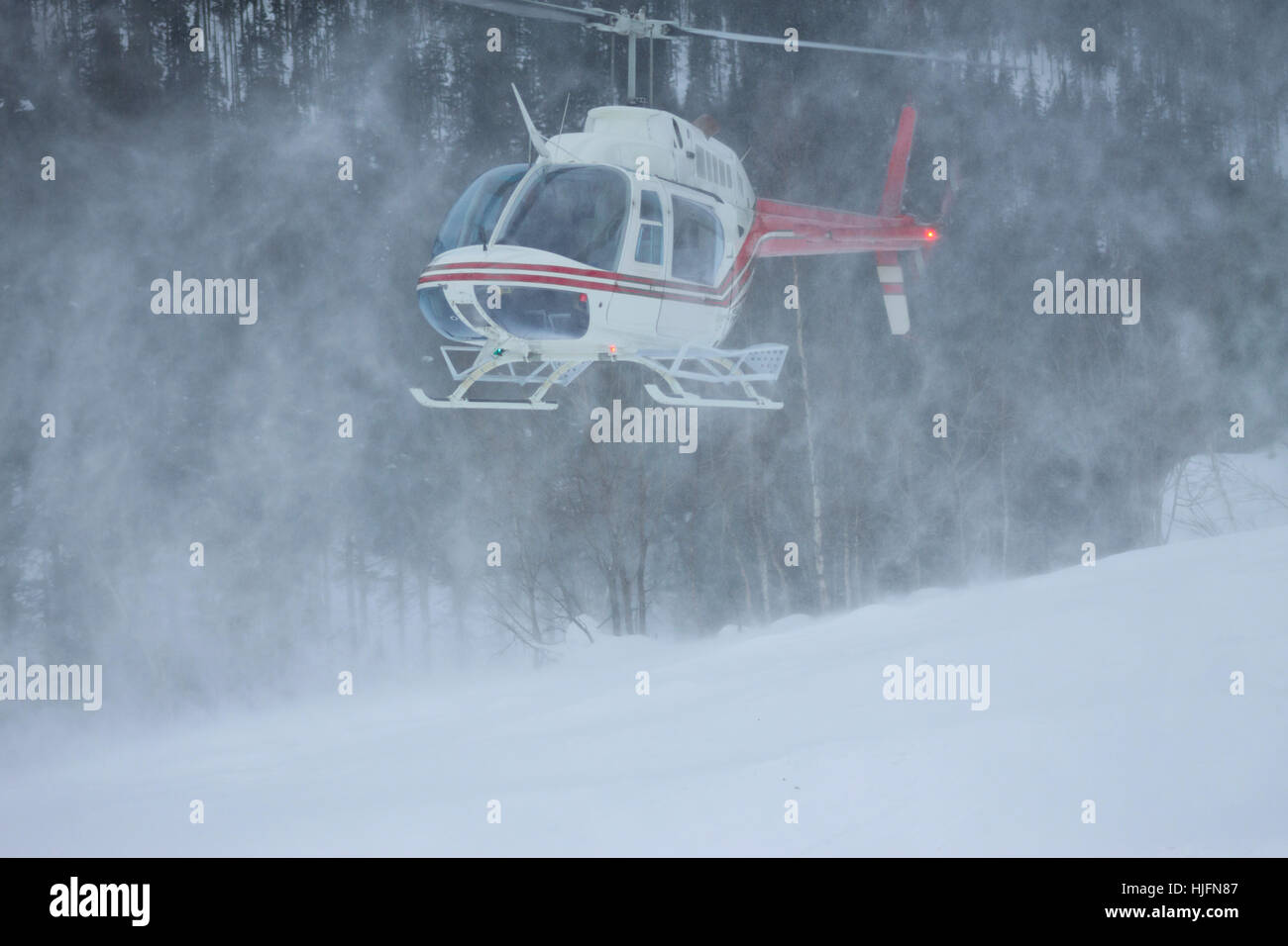 The helicopter landed in the mountains in winter, raising a cloud of ...