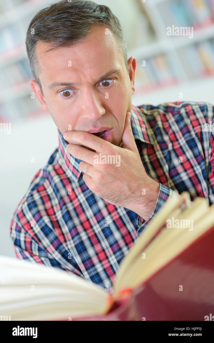 Man reading book, shocked expression Stock Photo - Alamy