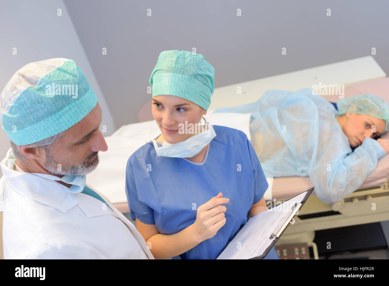 Patient face down on bed, doctors consulting clipboard Stock Photo - Alamy