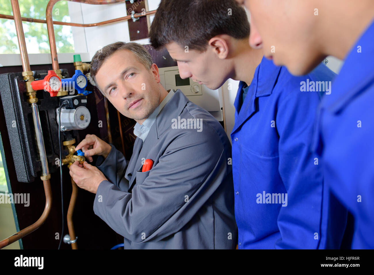 Tradesman training two apprentices Stock Photo - Alamy