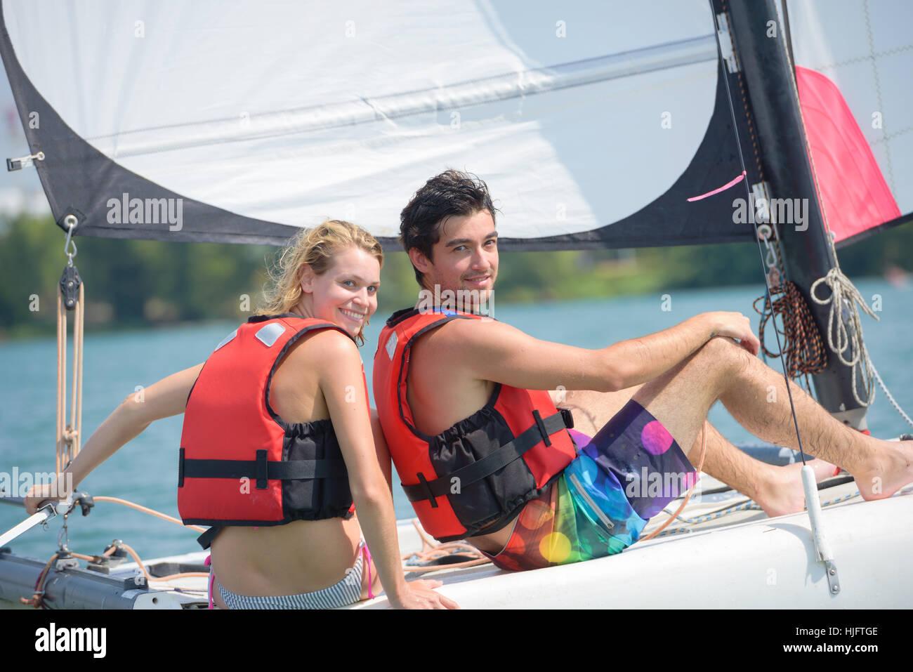 young couple steering a catamaran Stock Photo - Alamy