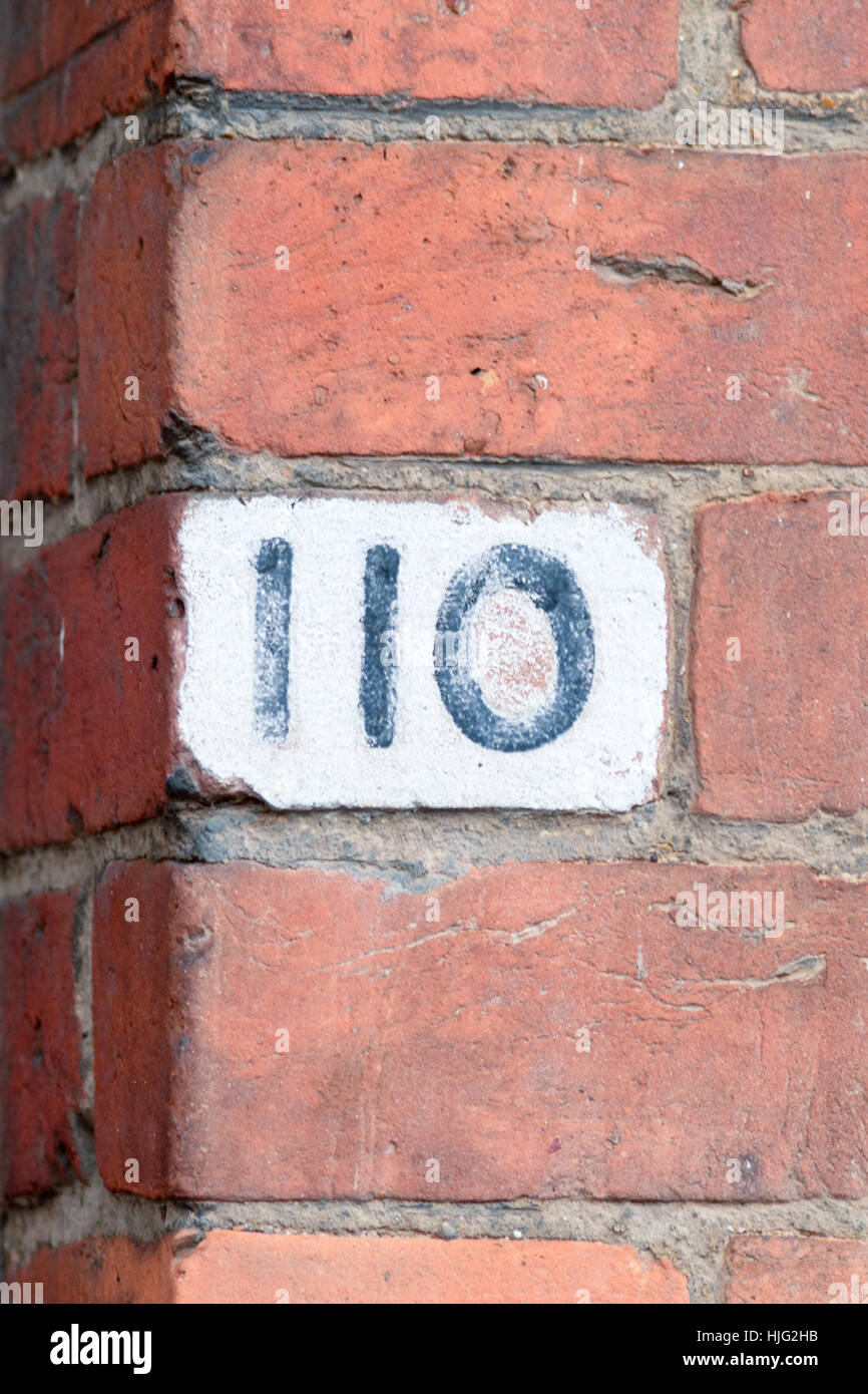 House number 110 sign painted black with white background on red brick ...