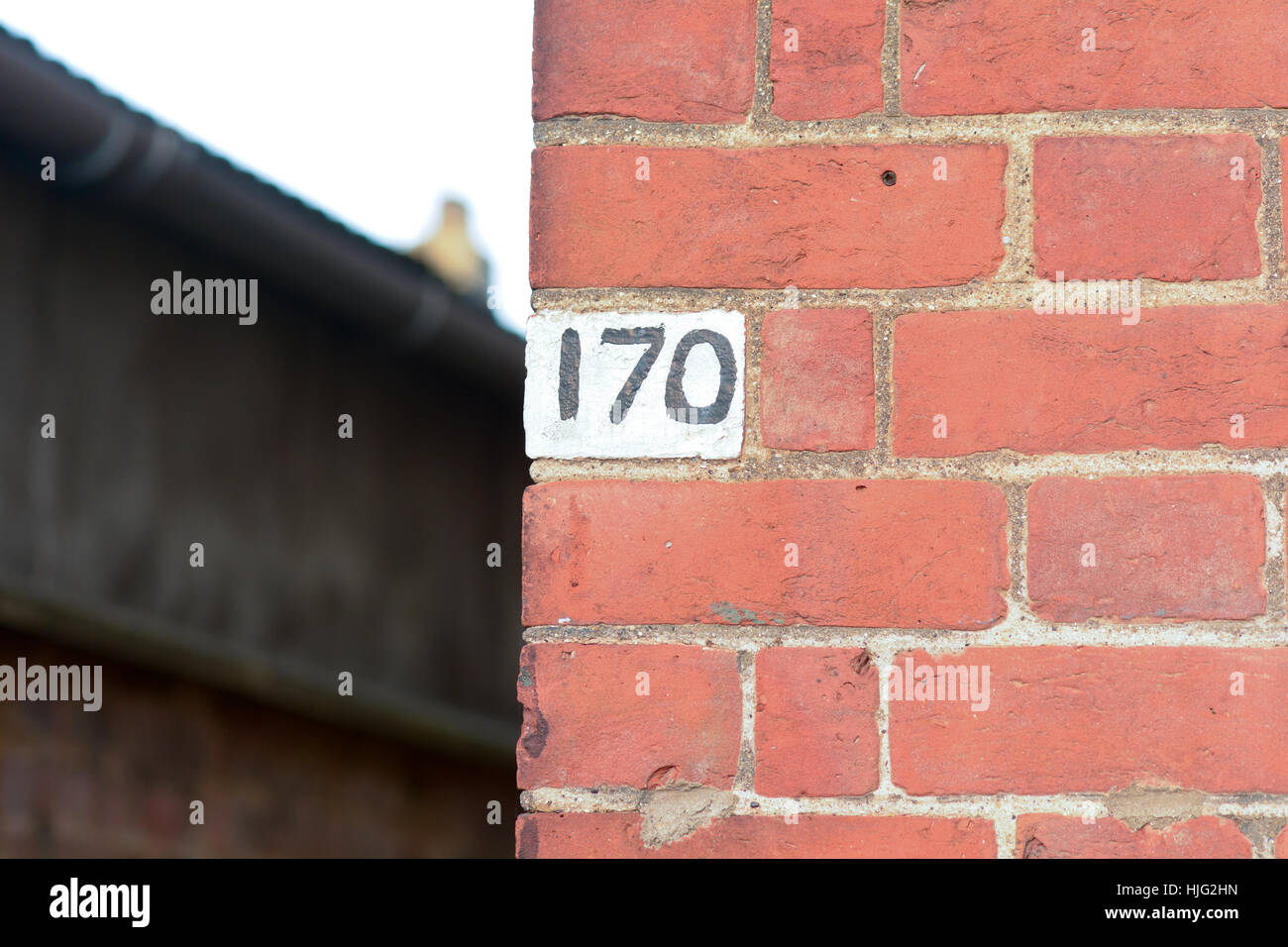 House number 170 painted black with white background on red brick wall ...