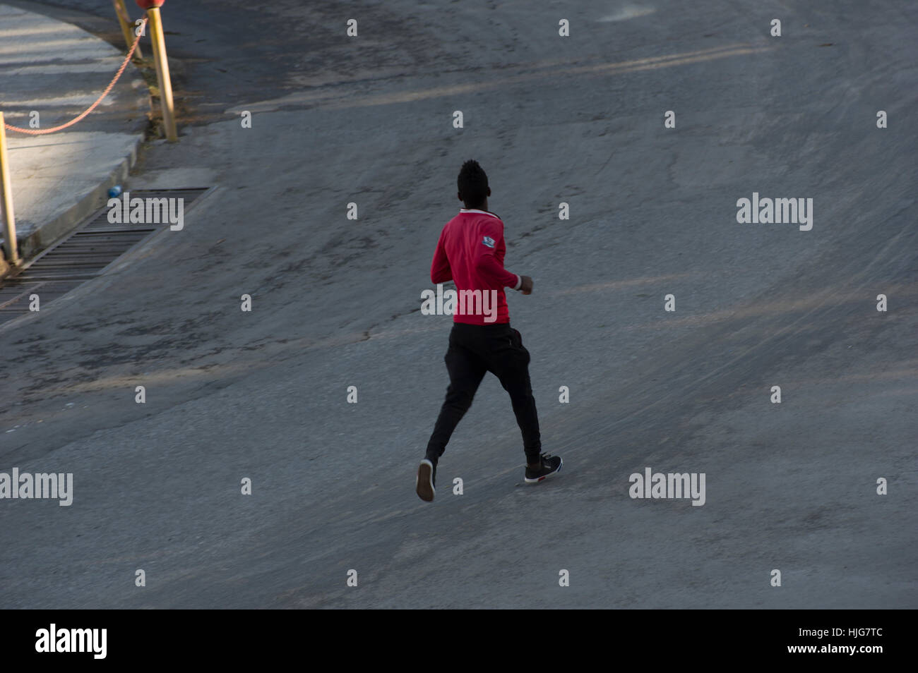 Man running or jogging in a street, face not visible, wearing a red ...