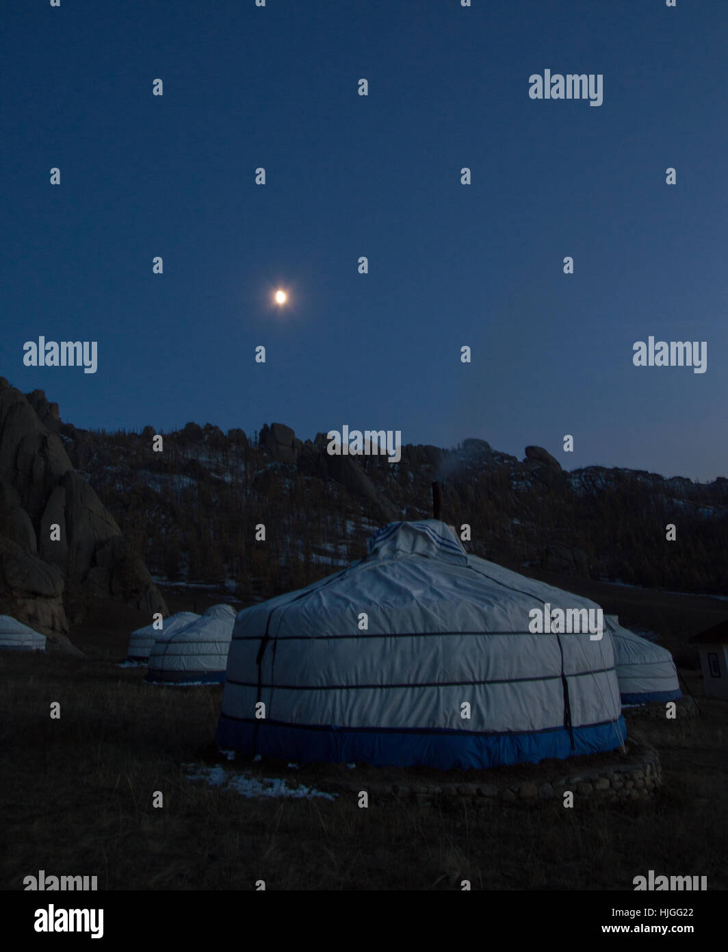Several white and blue canvas Mongolian yurts in the moonlight with the ...