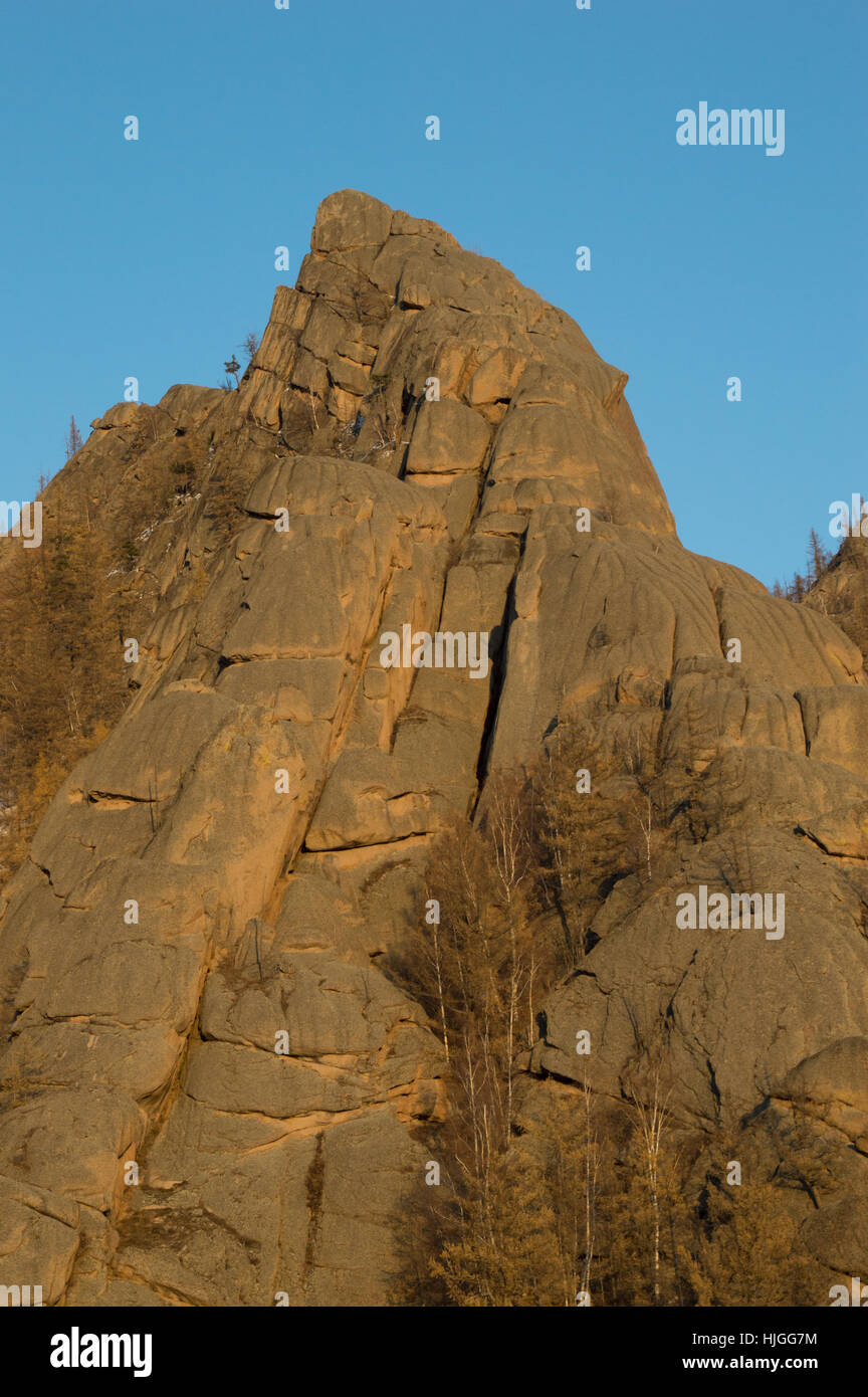 Rugged stone mountain with vertical fissures and sparse vegetation with ...