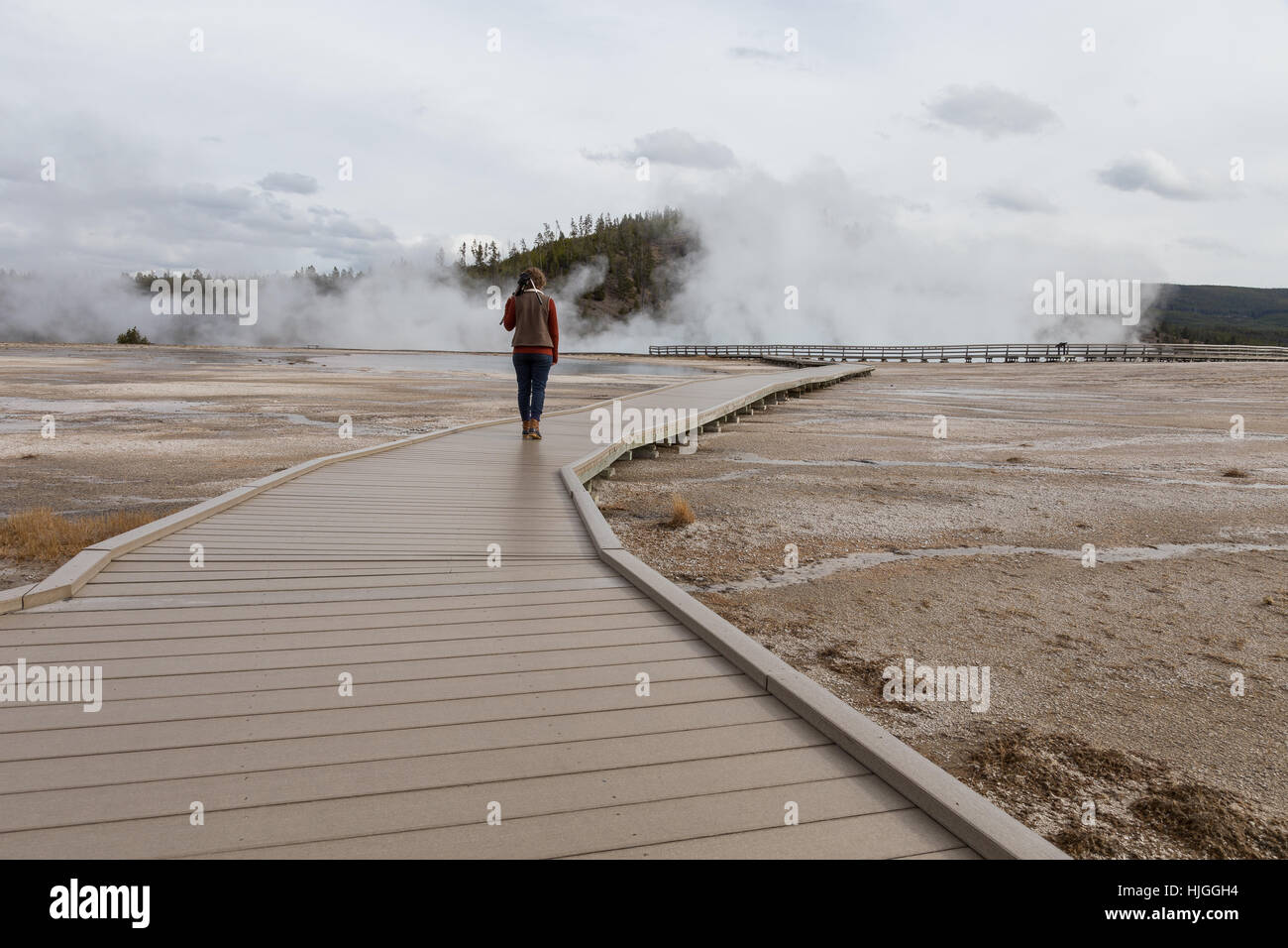 A woman walks along the boardwalk in Midway Geyser Basin in Yellowstone ...