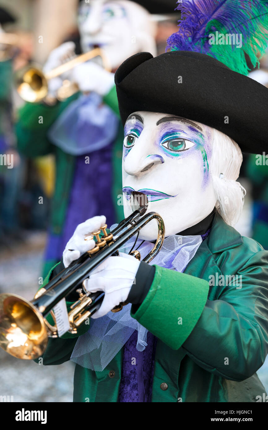 Group of medieval masks in green and purple costumes playing trumpet at ...