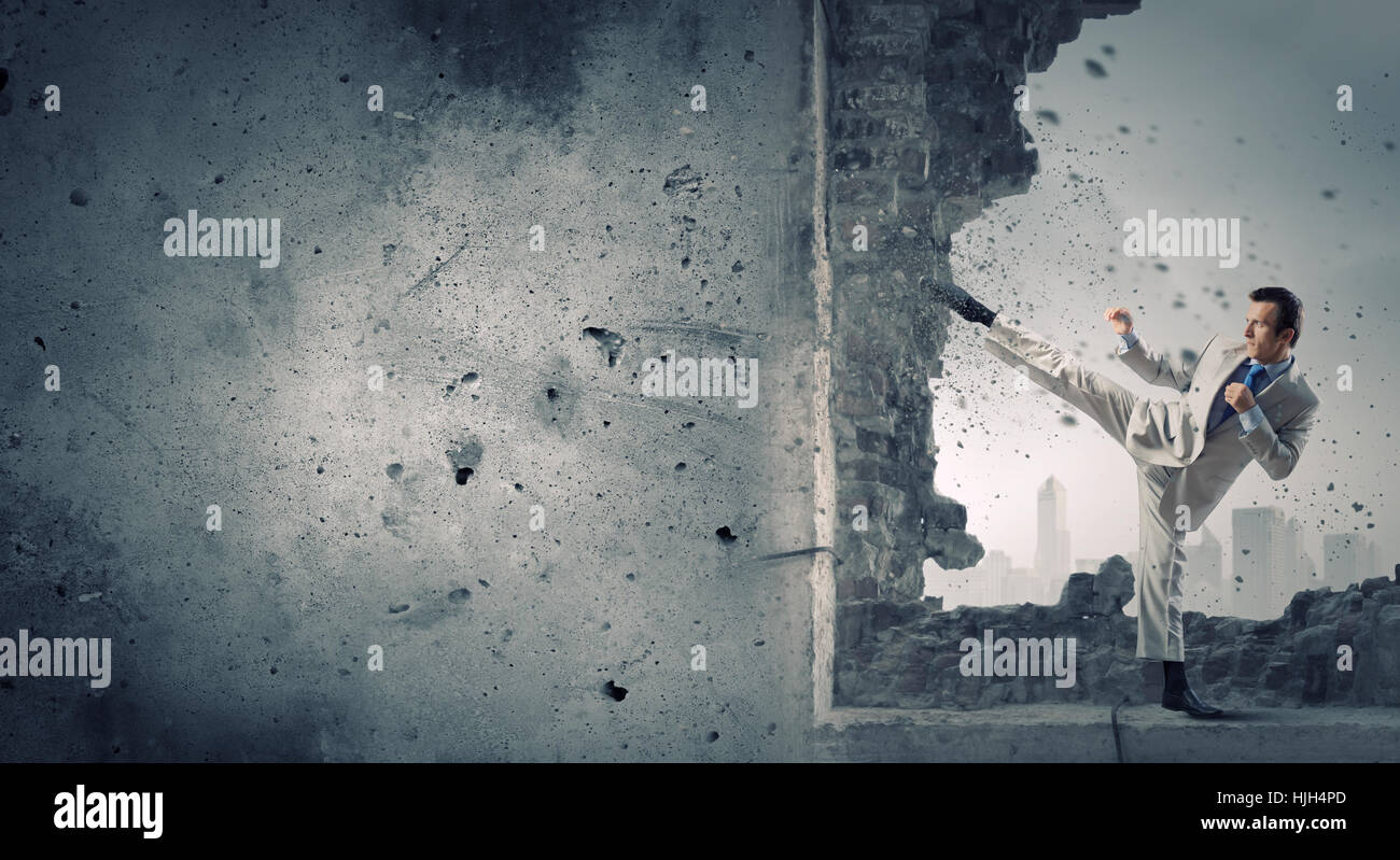 Businessman breaking stone wall with karate kick hi-res stock ...