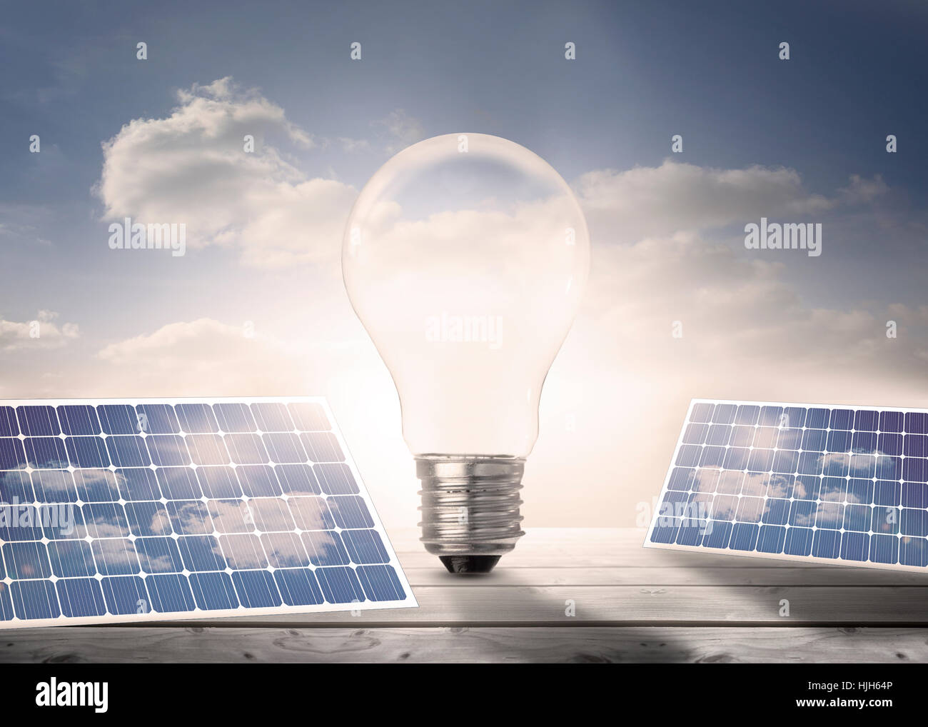 Light bulb and solar panels standing on floorboards in the cloudy blue ...