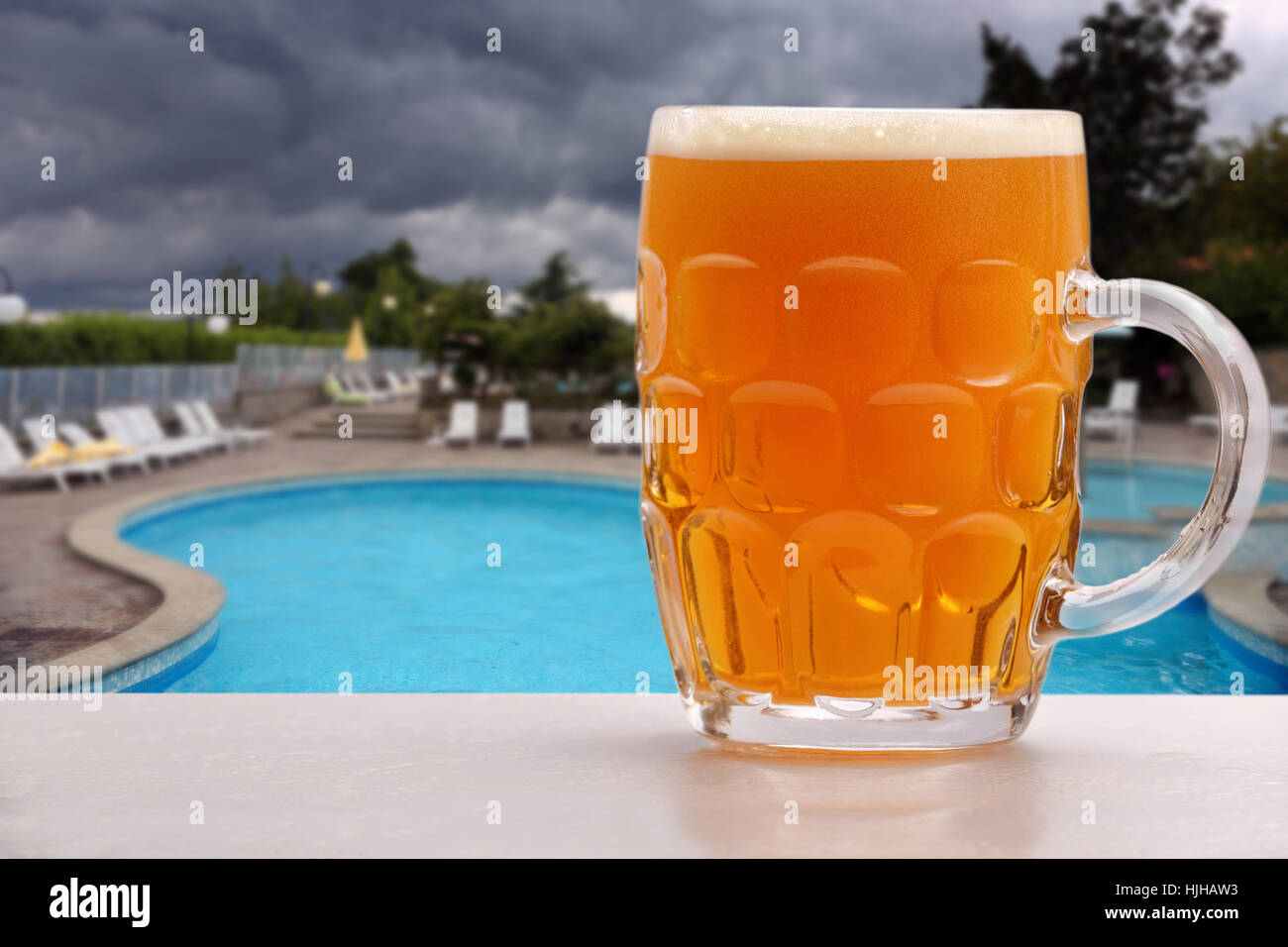 Pint of beer on stormy weather at the swimming pool background with ...