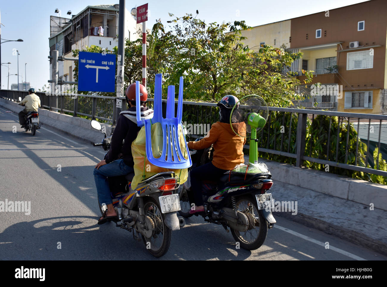 Carrying chairs and a fan on a scooter on the streets of Ho Chi Minh ...