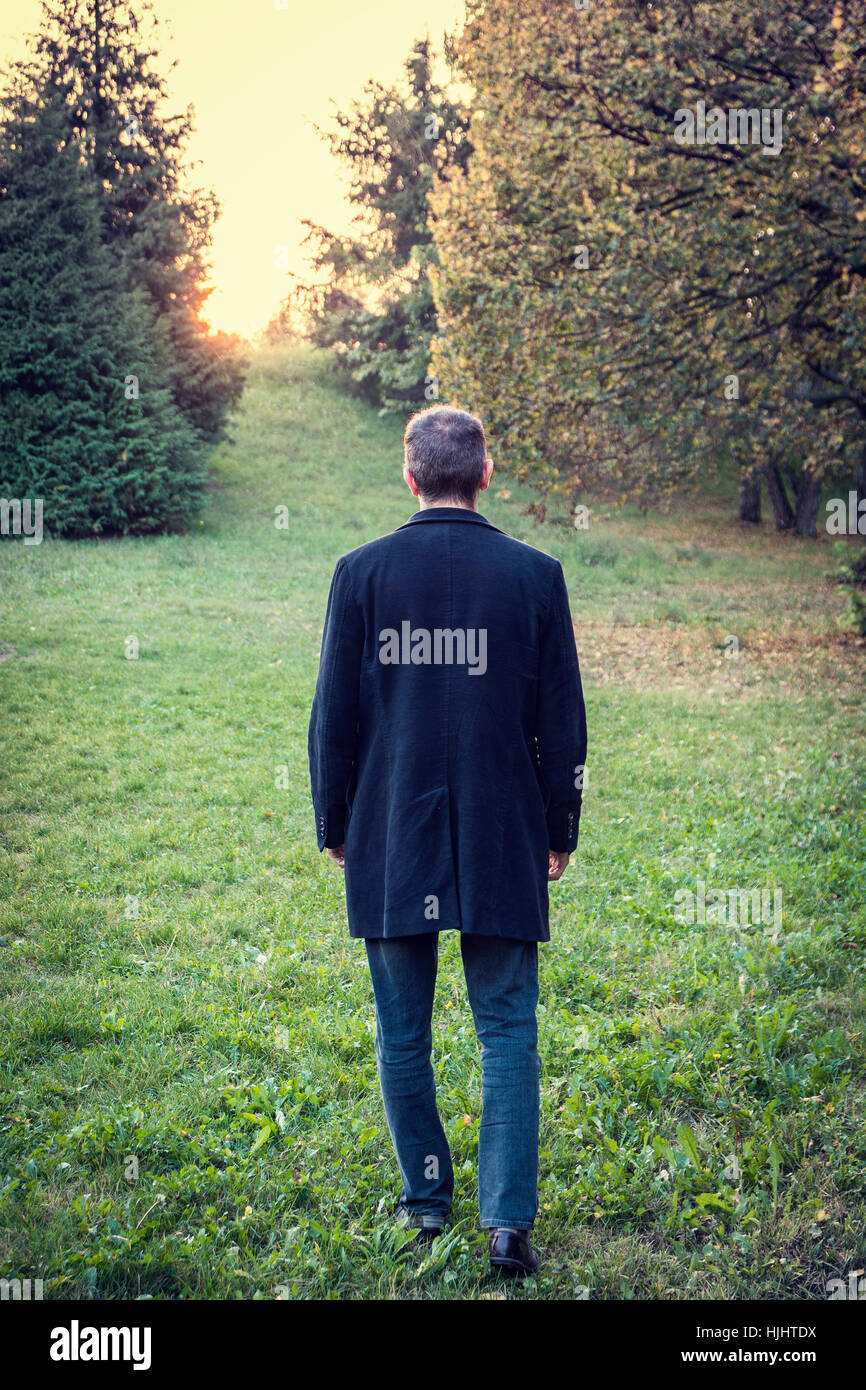 Man walking on grass meadow Stock Photo - Alamy