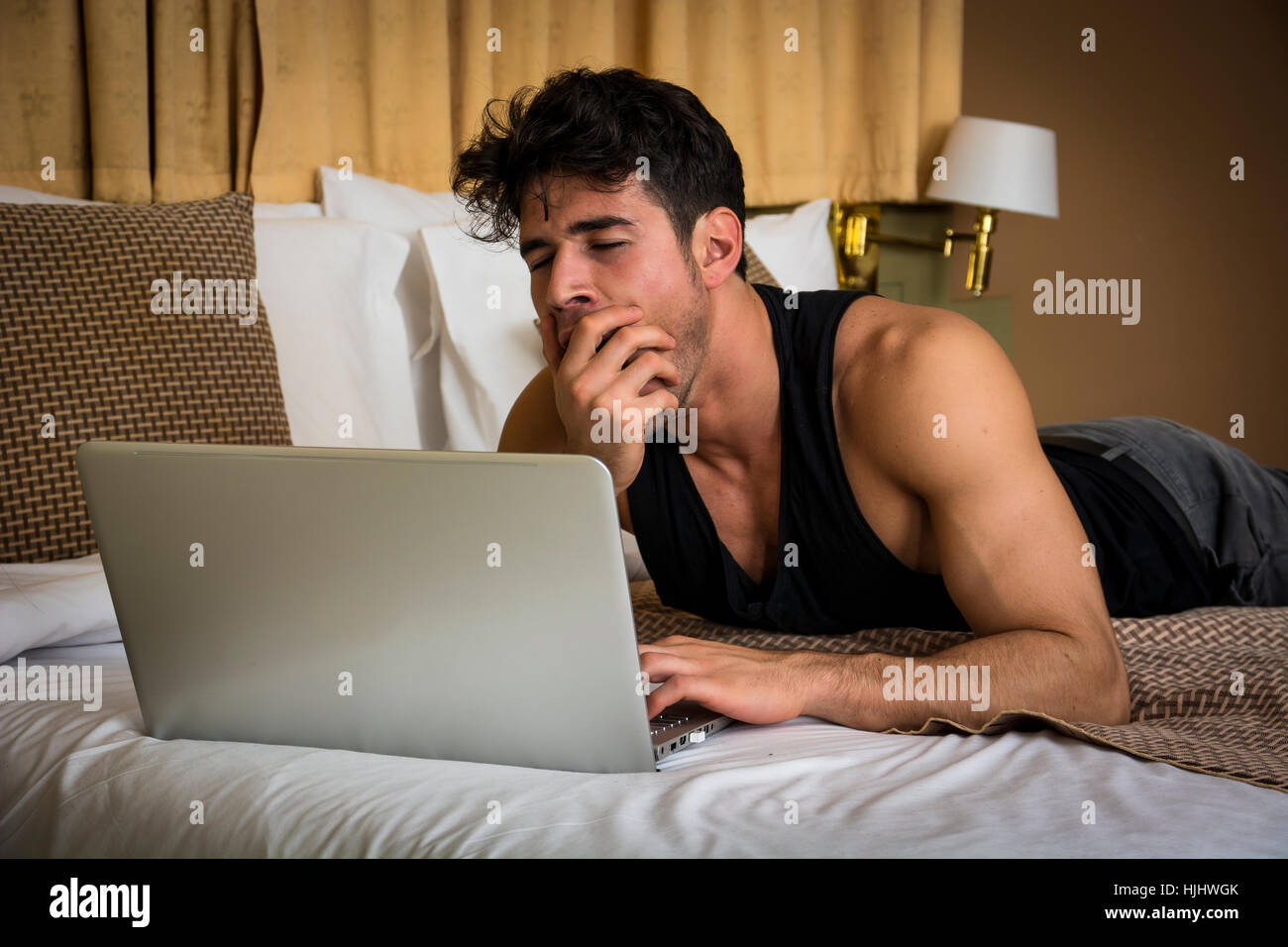 Young Man Doing Homework on Laptop in Bedroom Stock Photo - Alamy
