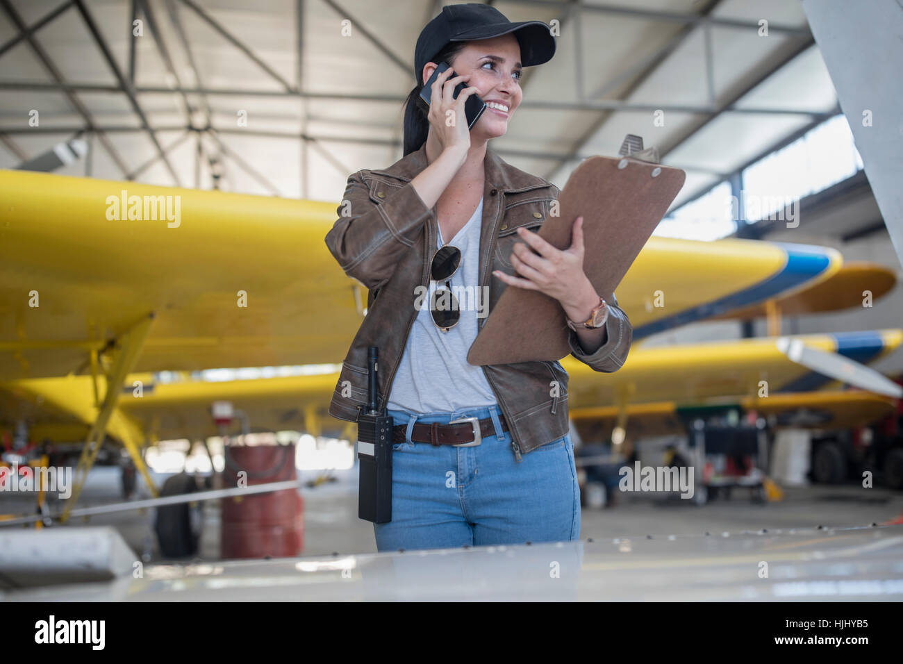 Female pilot talking on the phone in hangar Stock Photo - Alamy