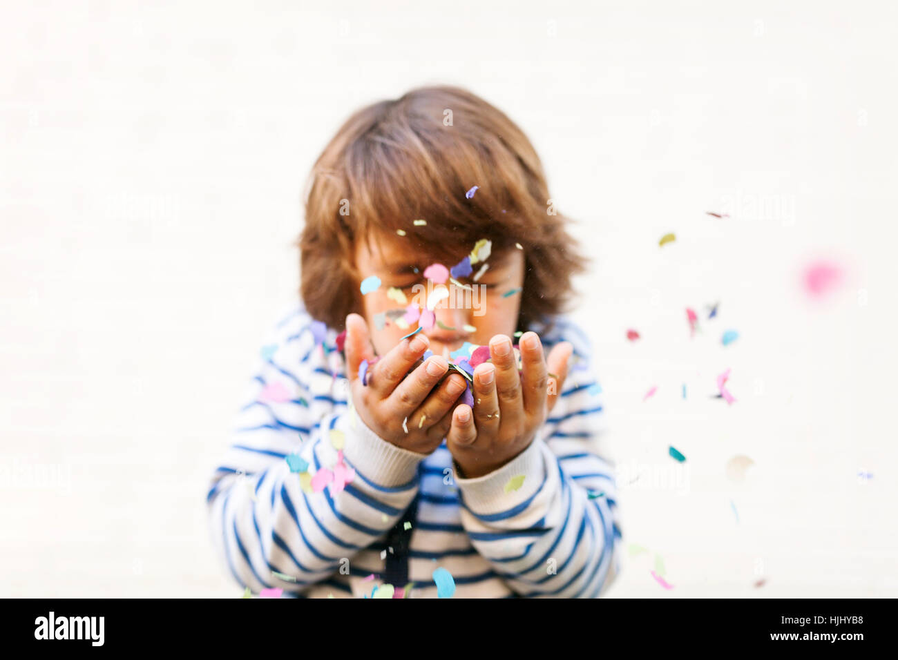 Boy blowing colorful confetti from there hands Stock Photo - Alamy