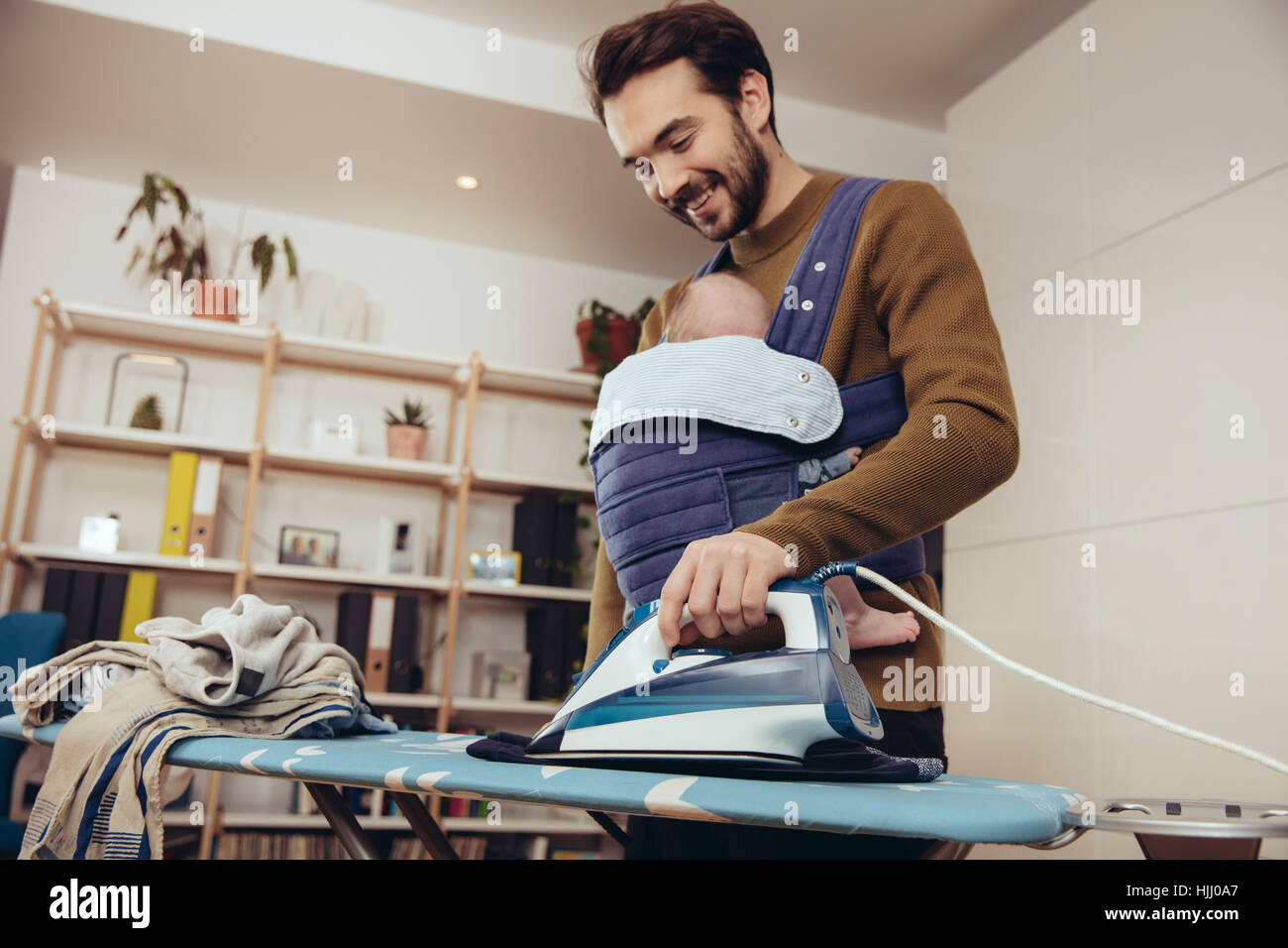 Father ironing and carrying his baby at home Stock Photo - Alamy