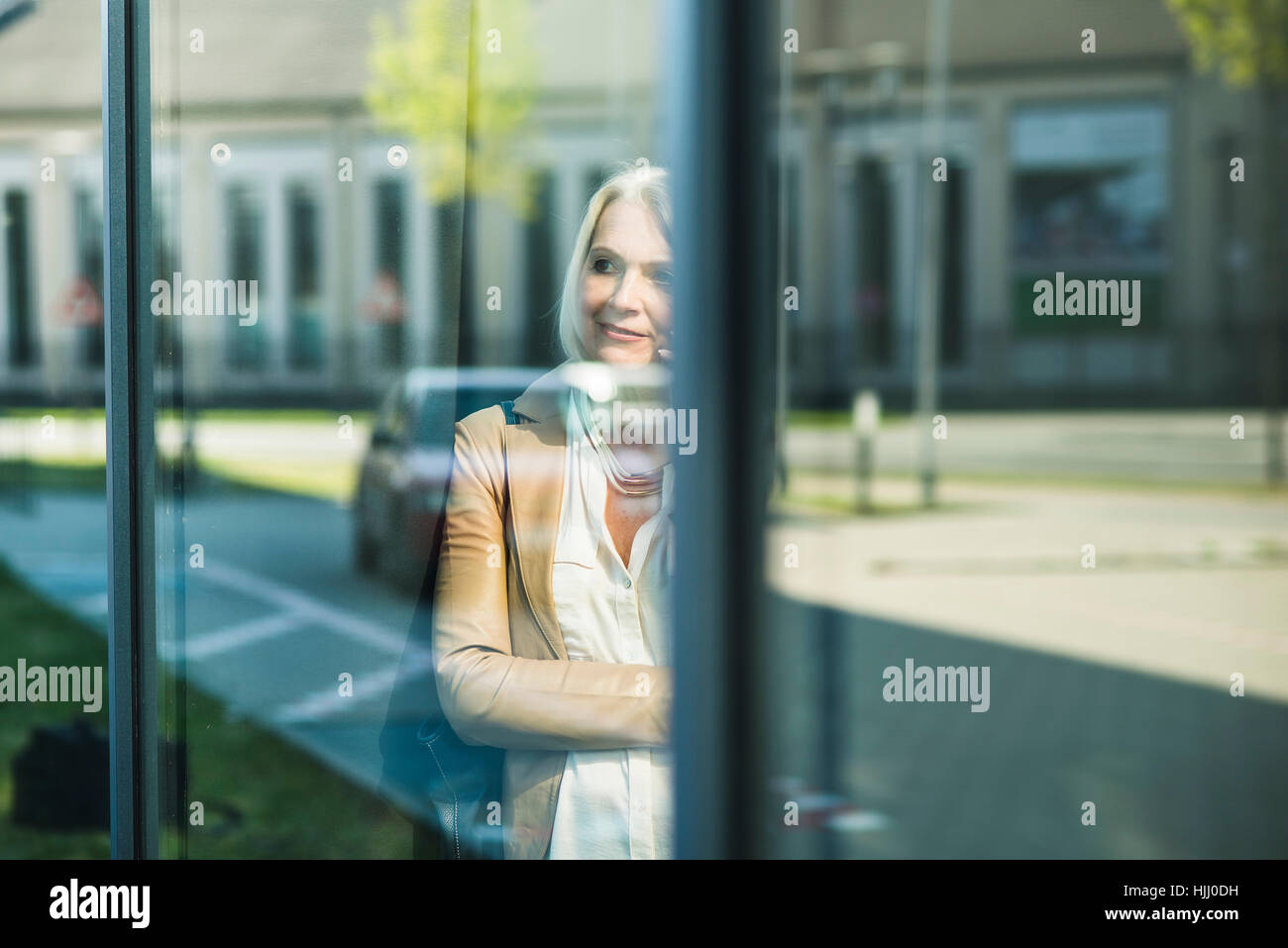 Mature woman looking at mirrored self at window pane Stock Photo - Alamy