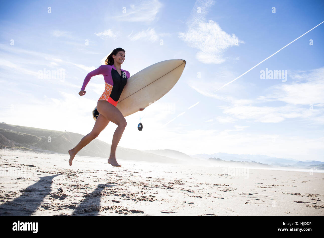 Woman carrying surfboard running on the beach Stock Photo - Alamy
