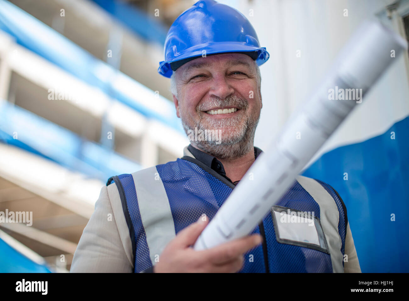 Engineer on construction site holding blueprint Stock Photo - Alamy