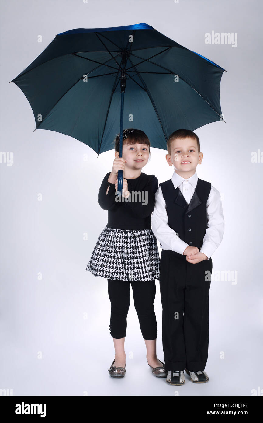 lovely boy and girl standing under umbrella Stock Photo - Alamy