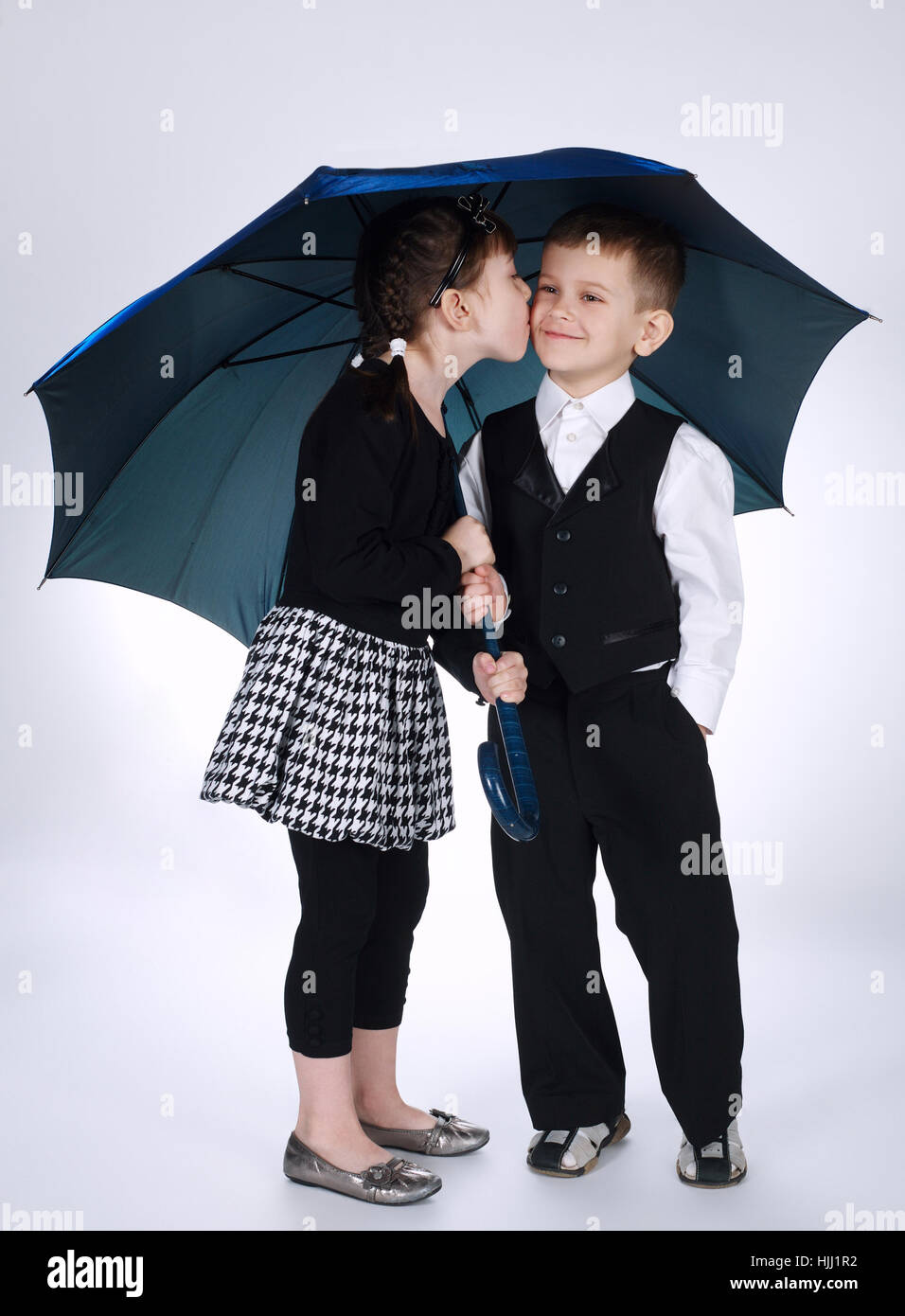 lovely boy and girl standing under umbrella Stock Photo - Alamy