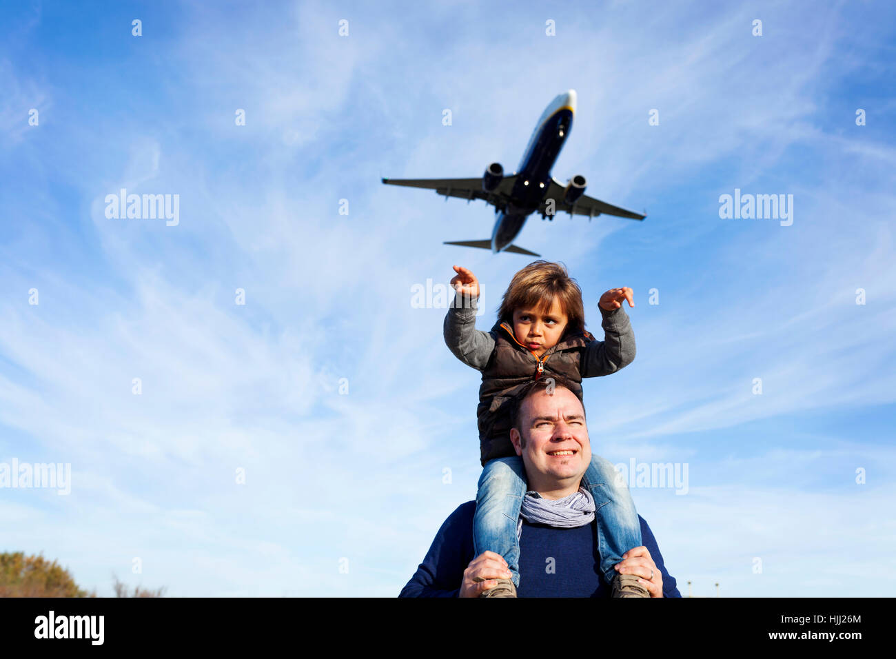Father carrying son on shoulders under flying airplane Stock Photo - Alamy