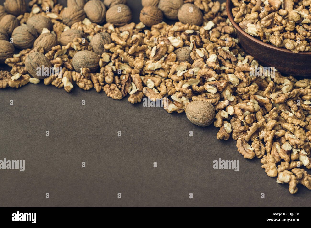 Walnut kernels and whole walnuts in brown ceramic bowl. Healthy organic ...