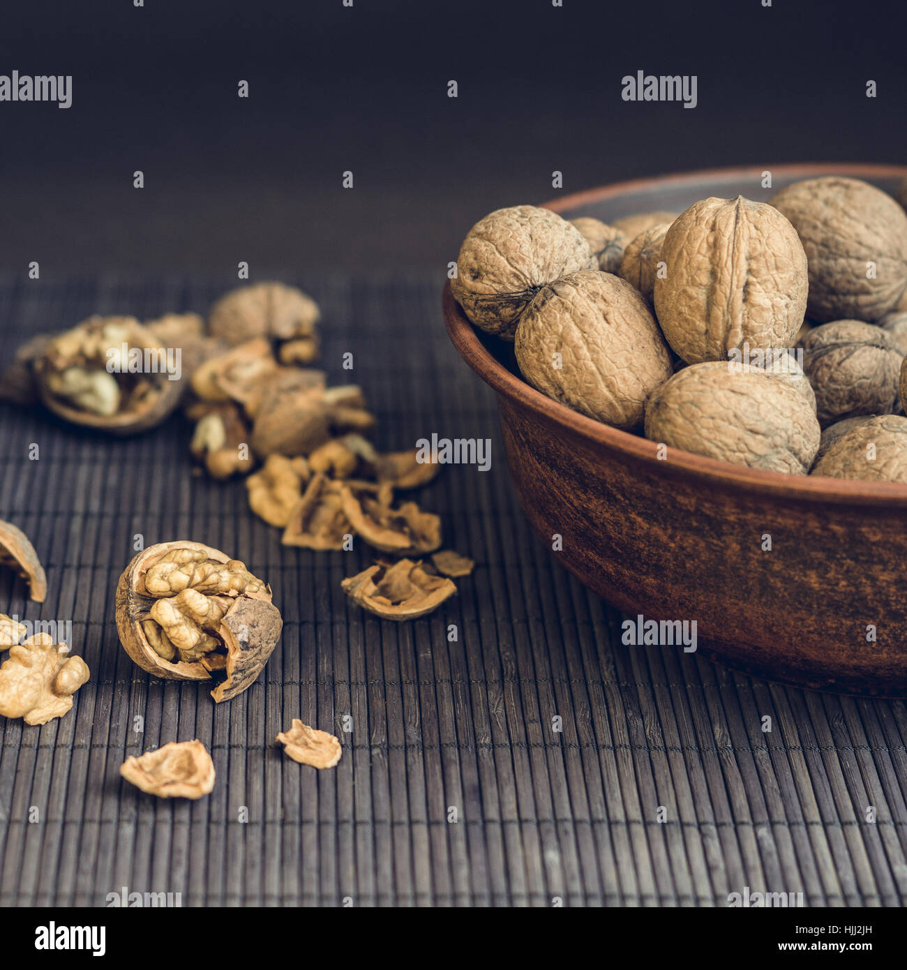 Walnut kernels and whole walnuts in brown ceramic bowl. Healthy organic ...