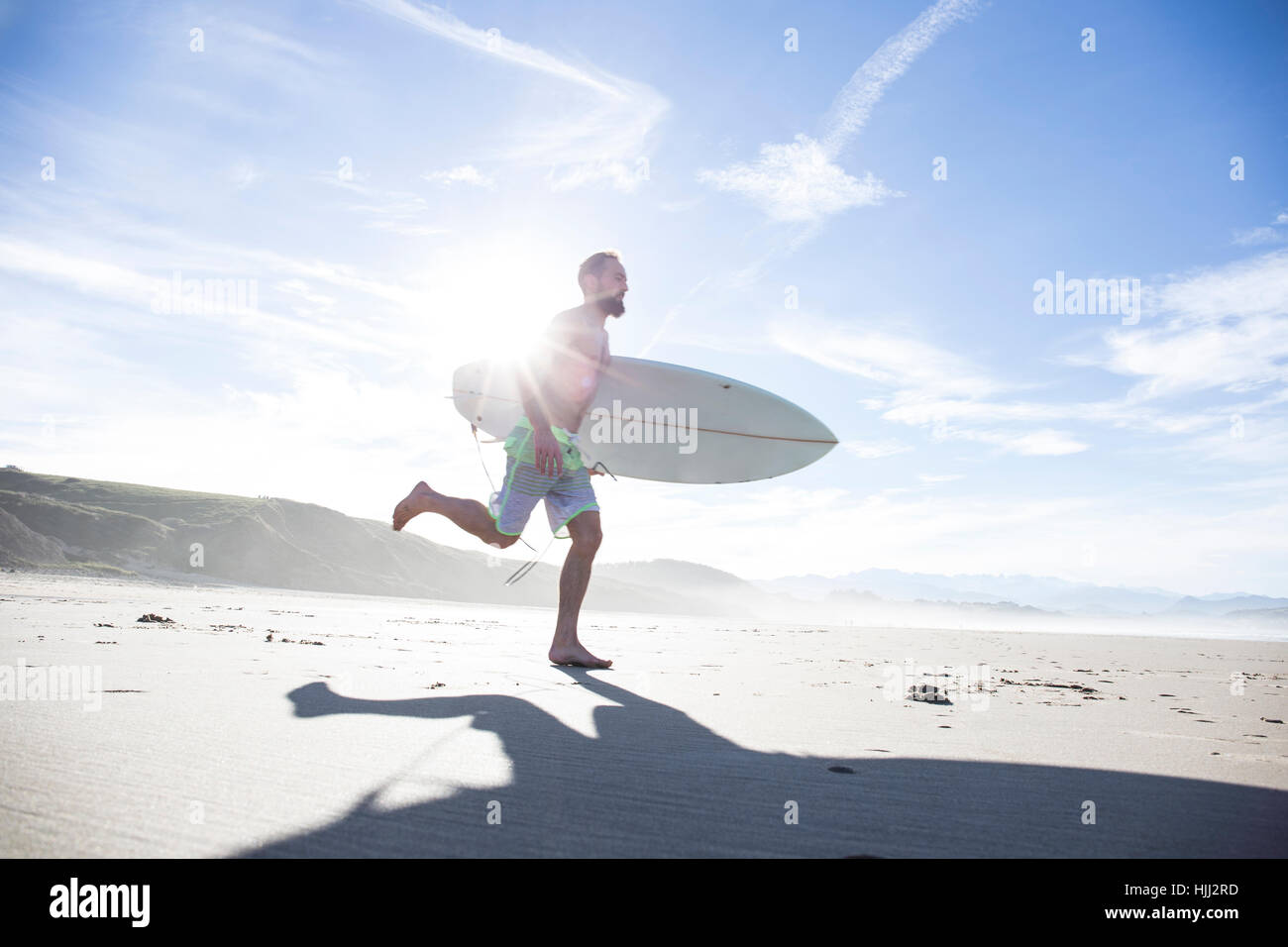 Man carrying surfboard running on the beach Stock Photo - Alamy