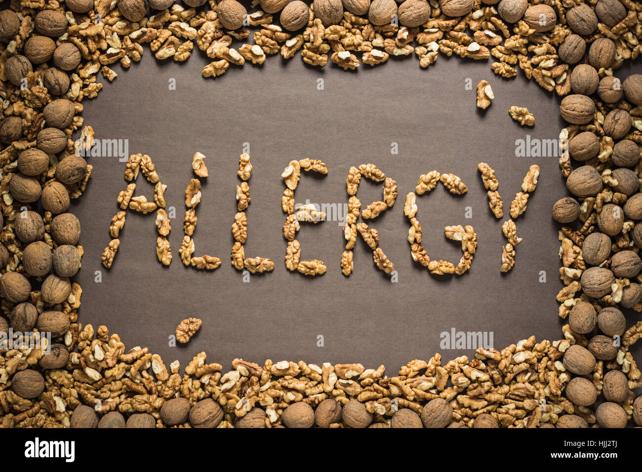The word "allergy" is written from the walnuts on a dark brown paper ...