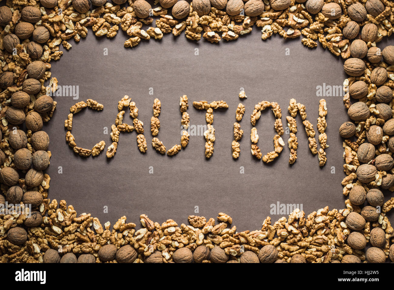 The word "caution" is written from the walnuts on a dark brown paper ...