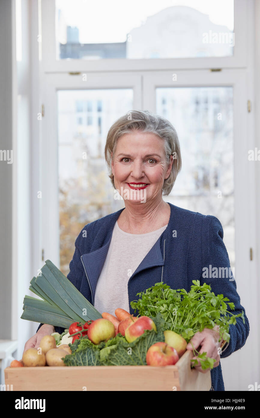 Portrait of smiling senior woman holding box with produce Stock Photo ...
