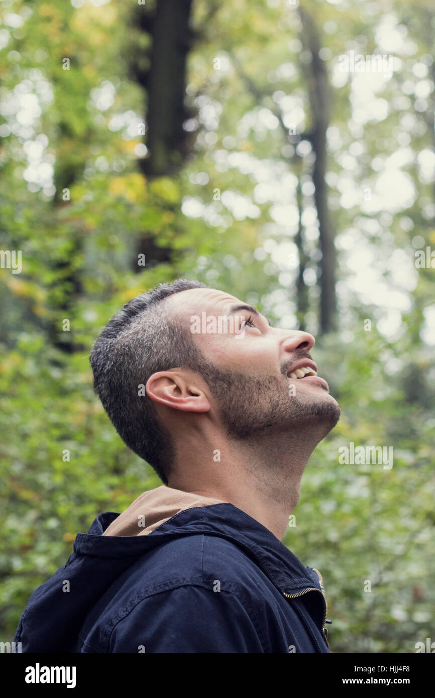Smiling man in the woods looking up Stock Photo - Alamy