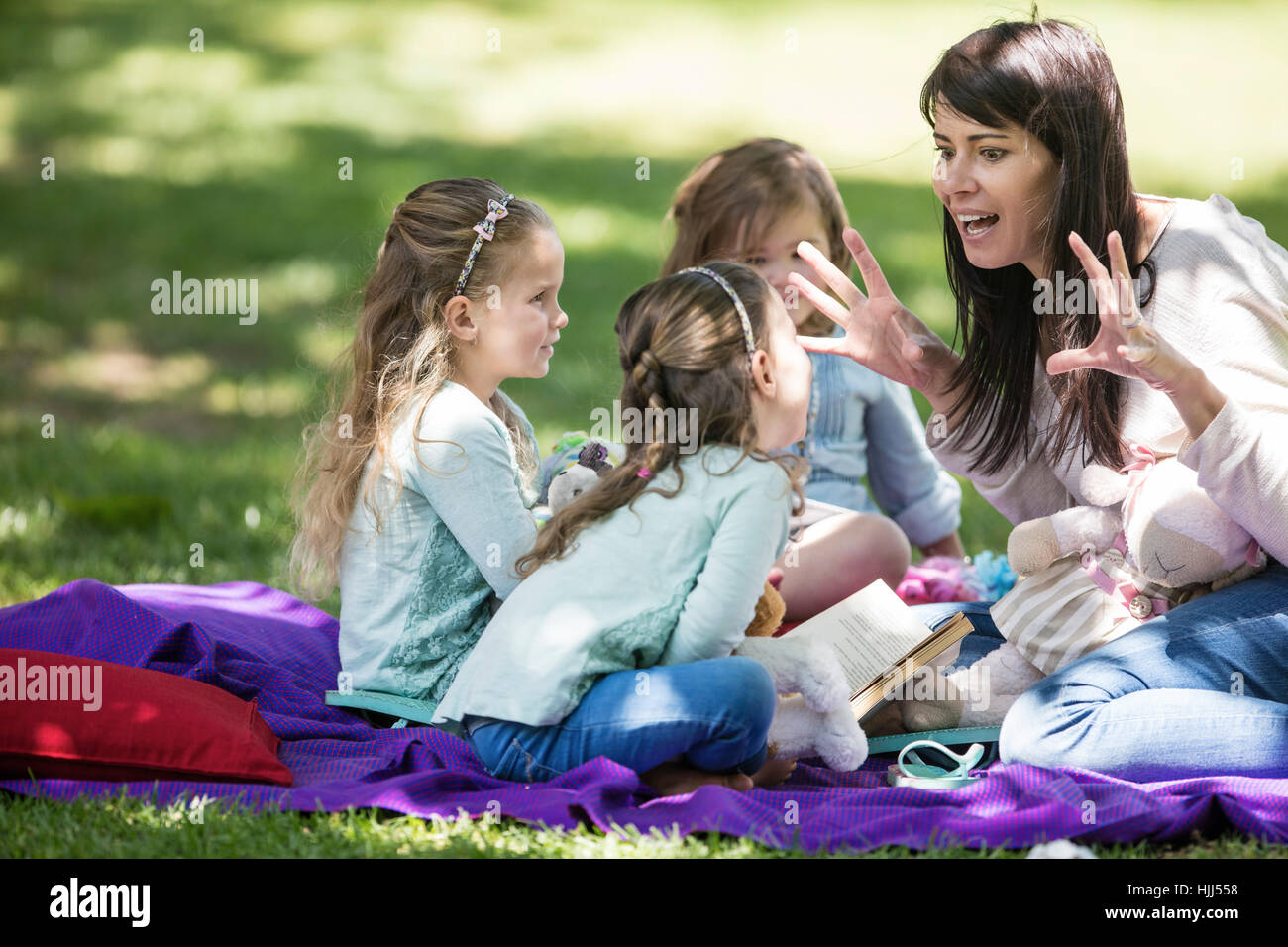 Mother telling stories to children on picnic blanket Stock Photo - Alamy