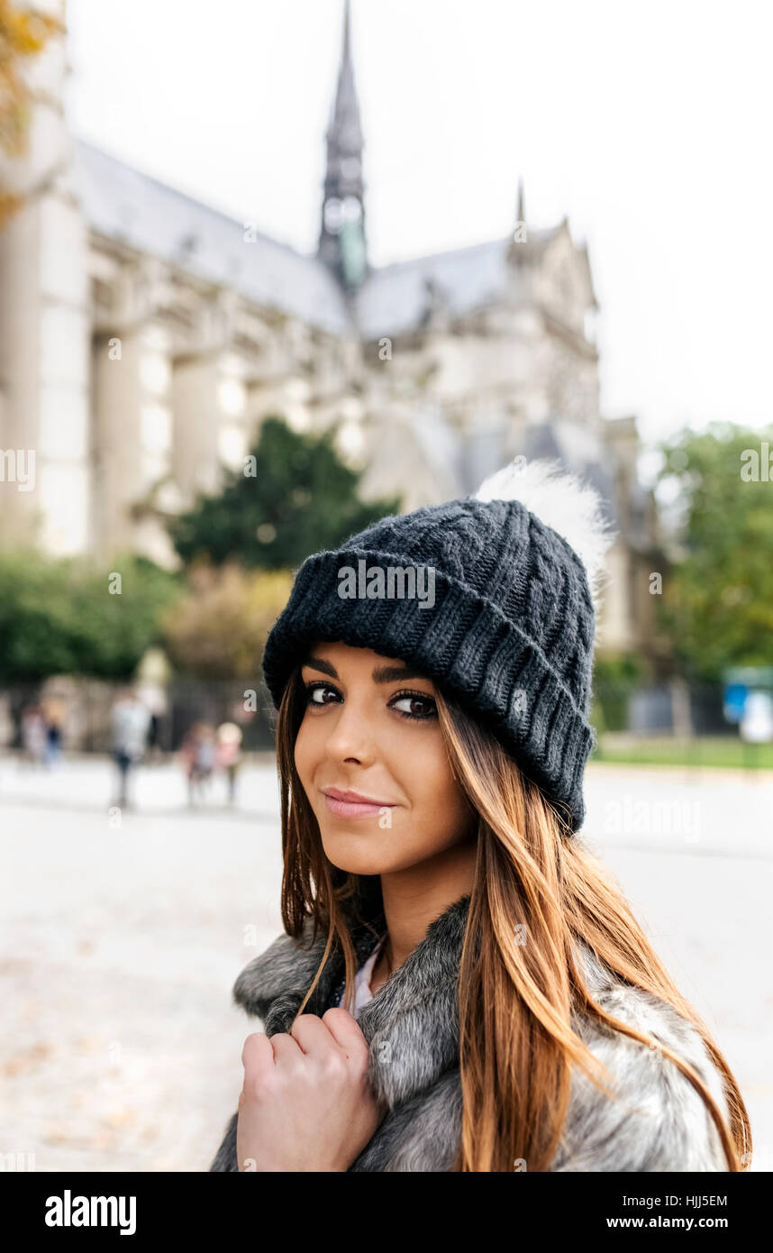France, Paris, portrait of happy young woman in front of Notre Dame ...