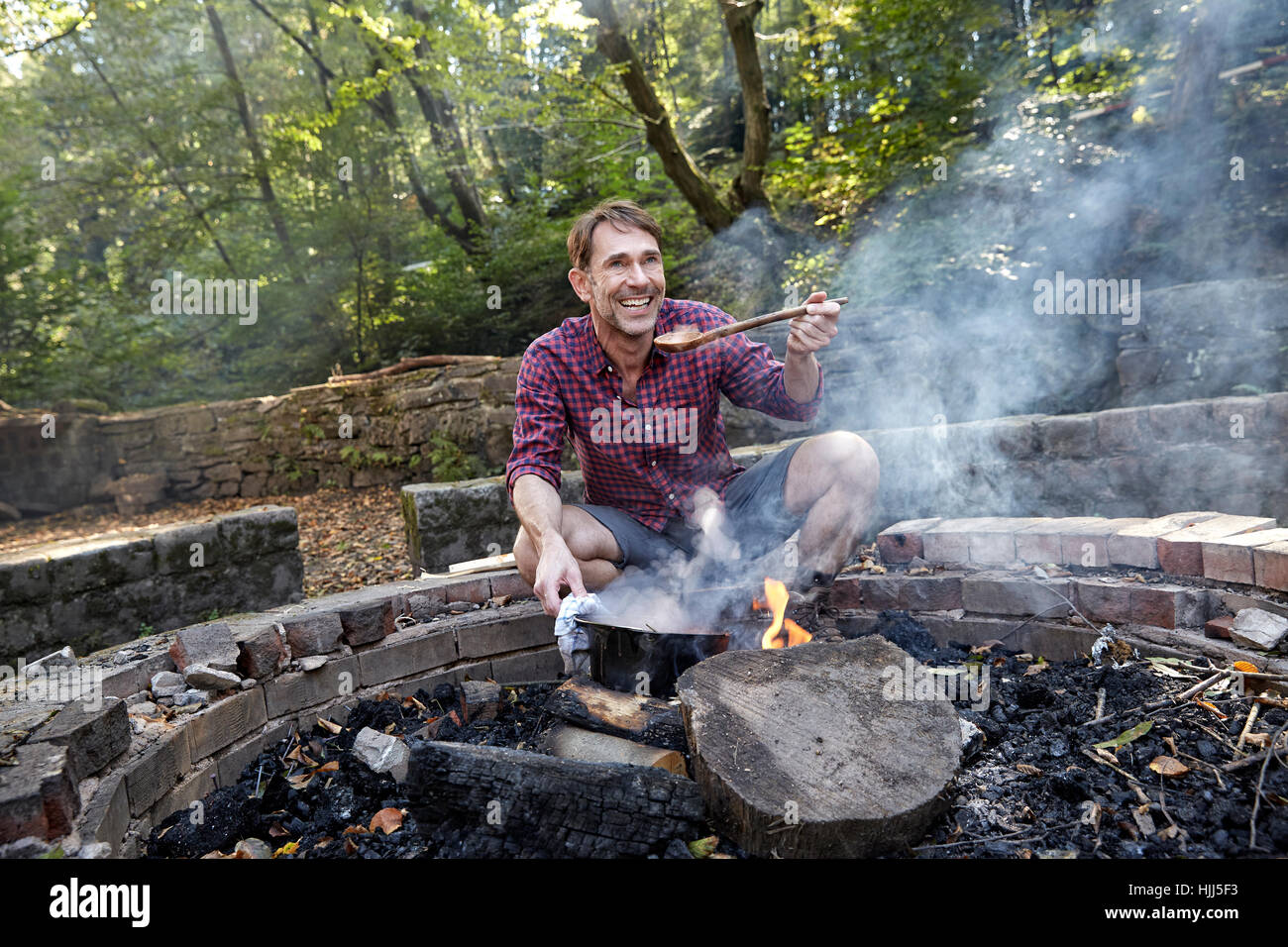 Man cooking at camp fire Stock Photo - Alamy
