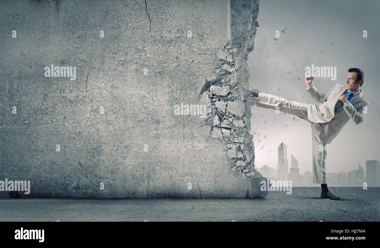 Businessman breaking stone wall with karate kick hi-res stock ...