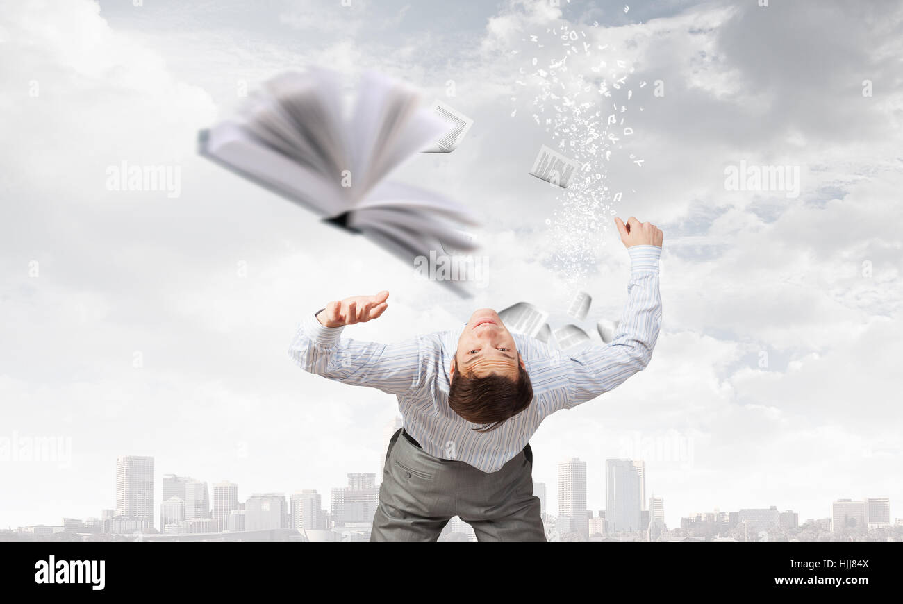 Businessman bent over and evading from book Stock Photo - Alamy