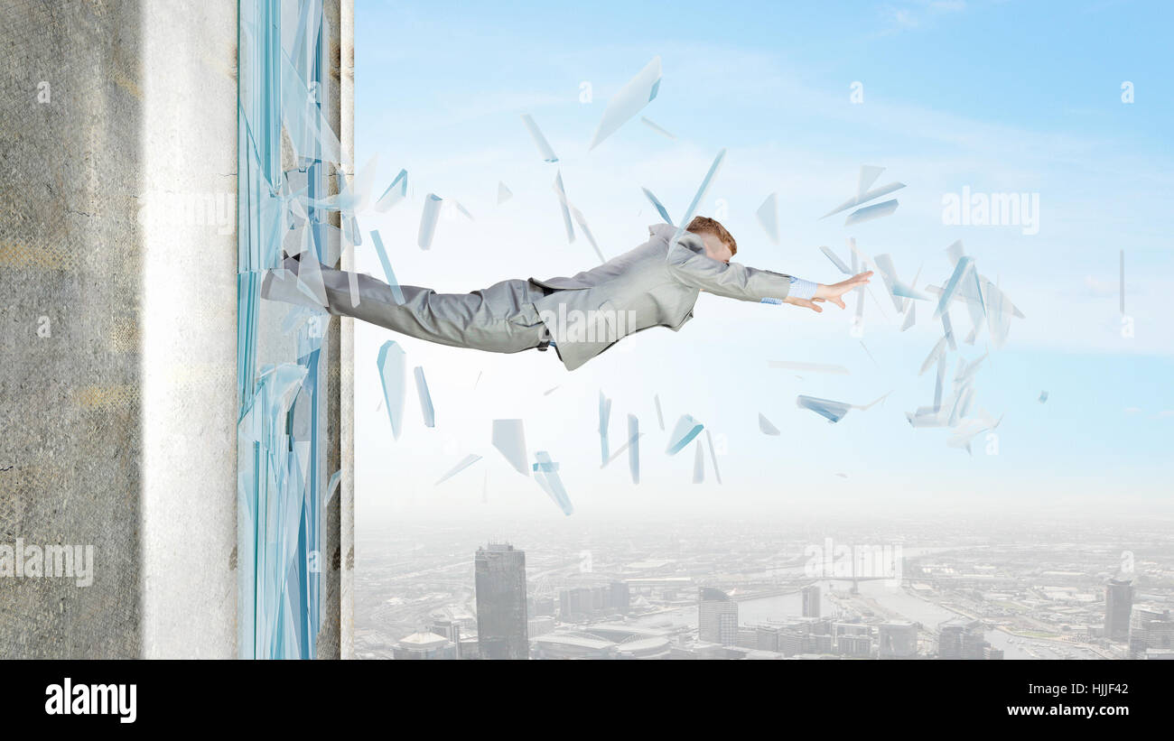 Businessman jumping through glass window of office hi-res stock ...
