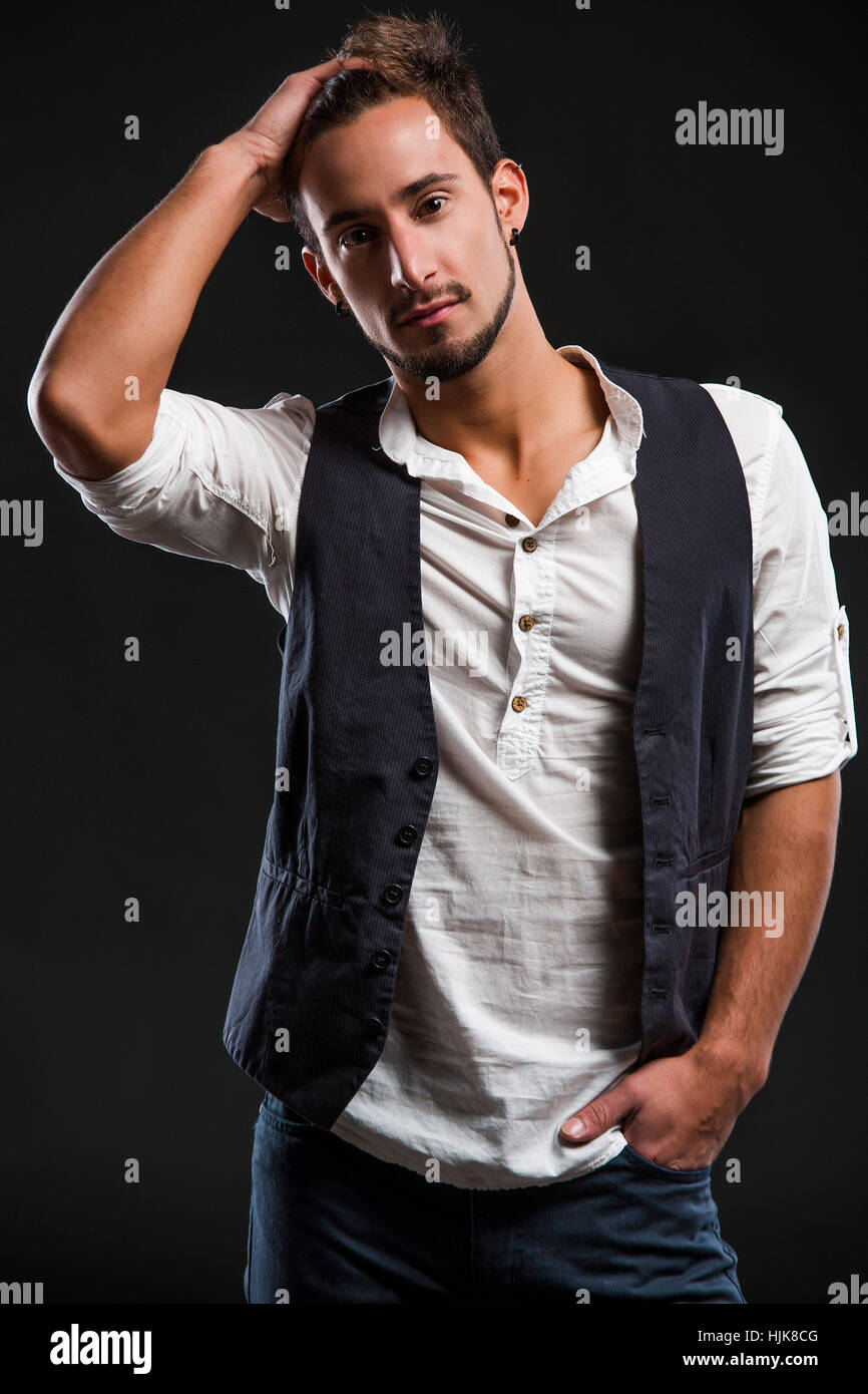 Studio portrait of a handsome and fashion young man, posing over a dark ...