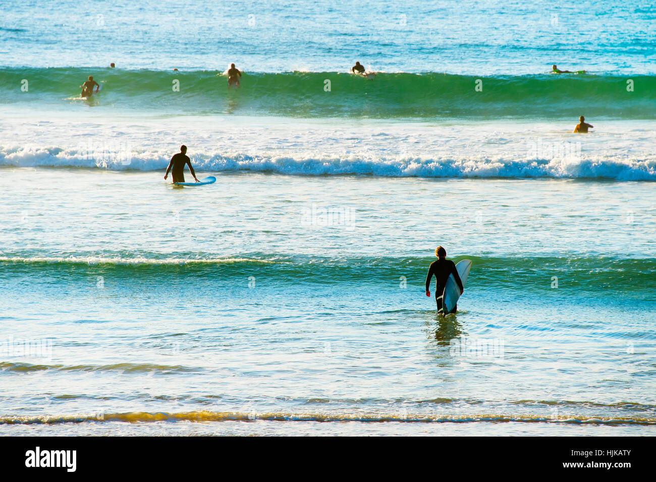 Lots of surfers surf in the ocean at sunset Stock Photo - Alamy