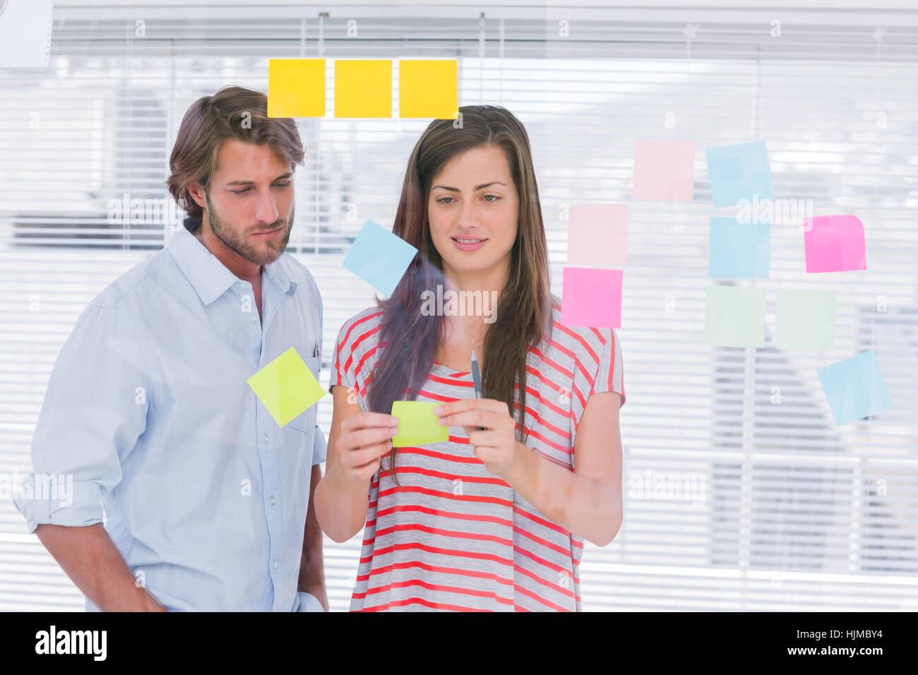 Colleagues reading sticky note in creative office Stock Photo - Alamy