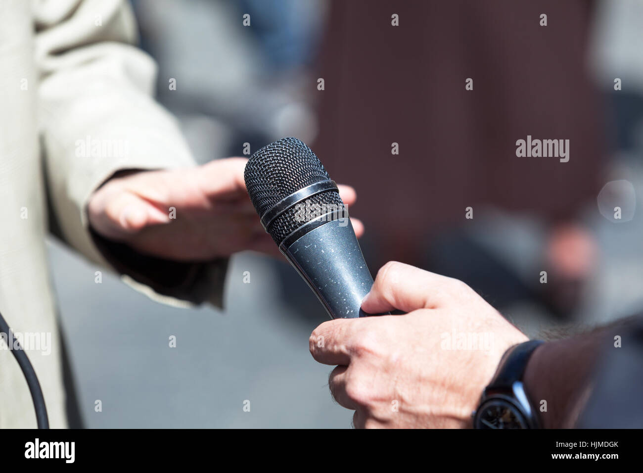 Reporter holding a microphone conducting an media interview Stock Photo - Alamy
